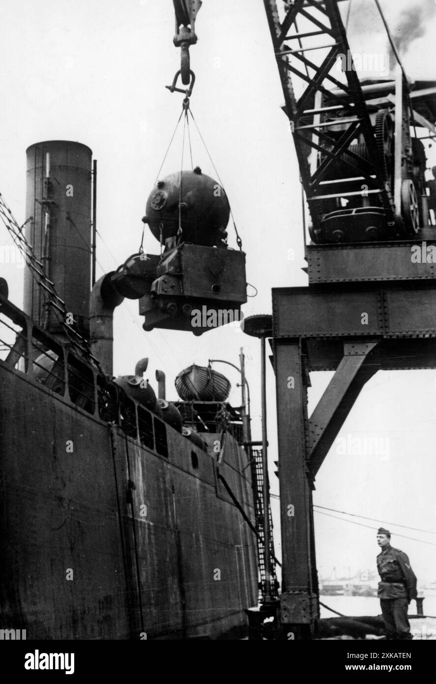 A crane in a harbor with a sea mine (bottom mine) on the hook. Undated ...