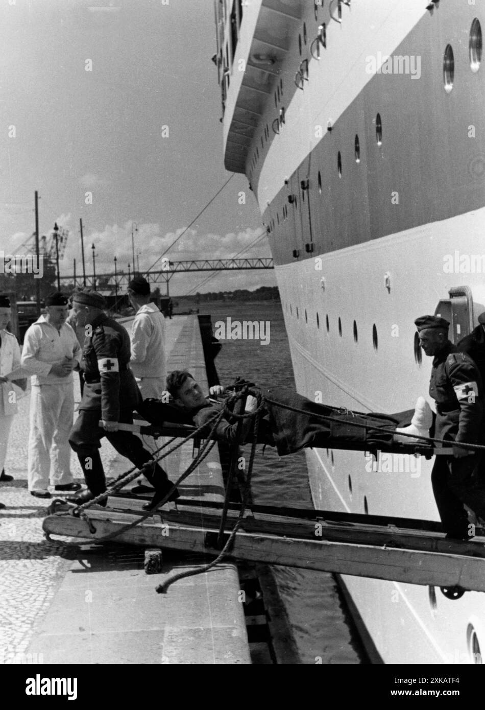 Orderlies carry a wounded soldier from a hospital ship in the harbor ...