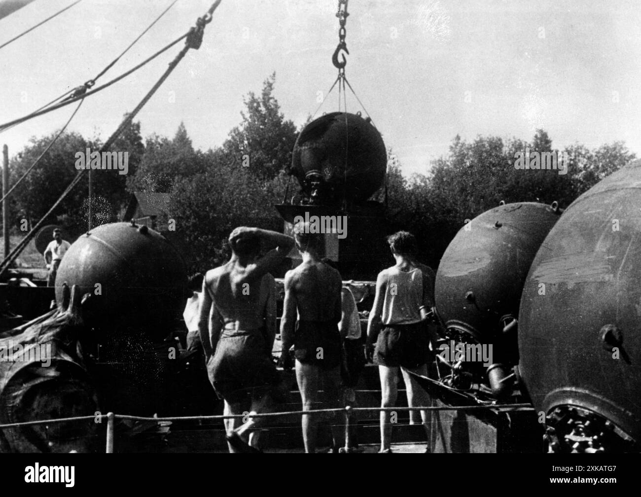 Sea mines are transferred from a supply ship to a smaller vessel in the ...