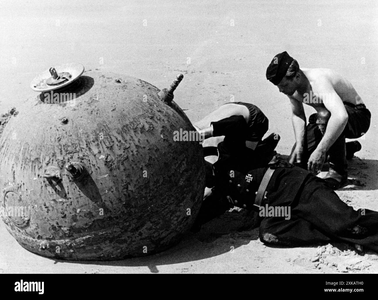 German soldiers defusing a sea mine washed up on the beach. Undated ...