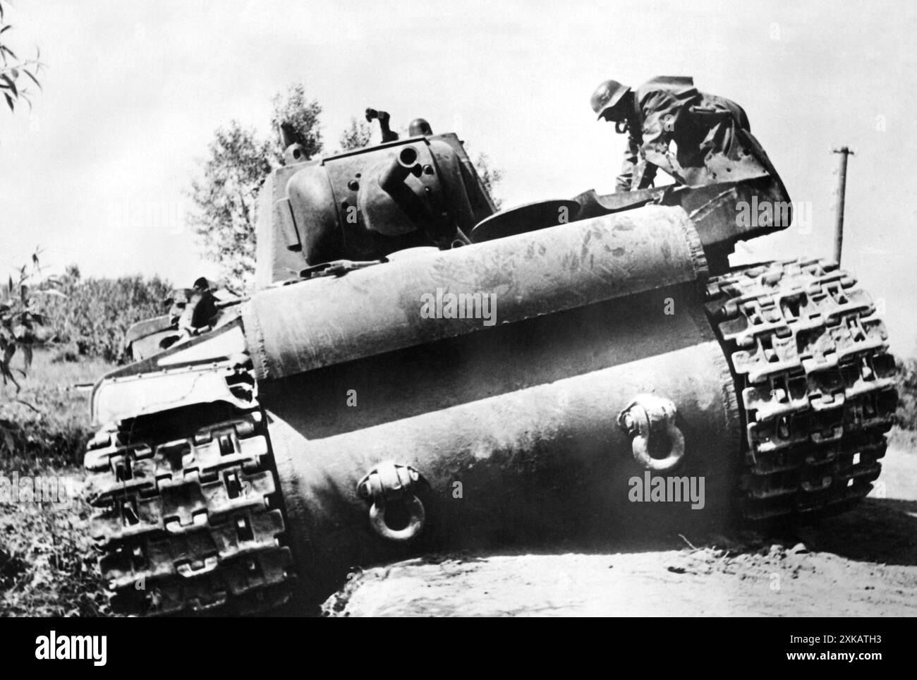 A German soldier examines a Russian KW-1 tank on a road in Lithuania ...