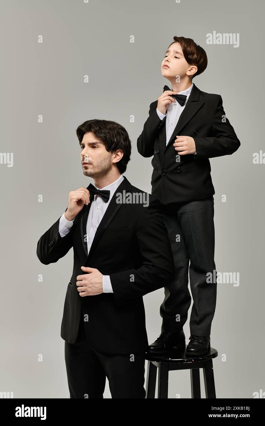 A father and his son stand side by side, both dressed in black suits ...