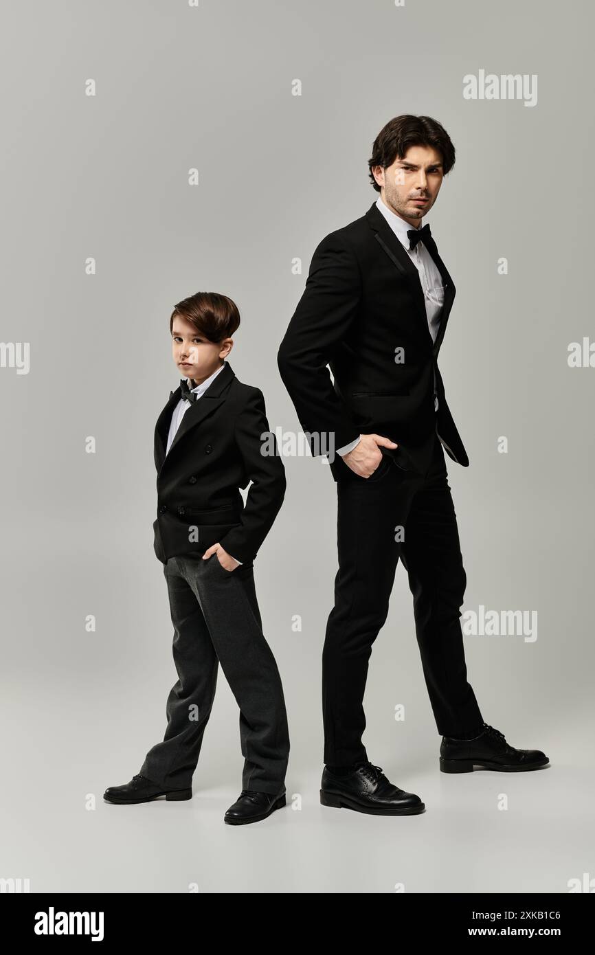 A father and son stand side-by-side in matching black suits, showcasing ...