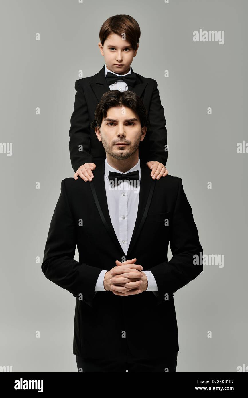 A father and son in matching suits, with the son sitting on his fathers ...