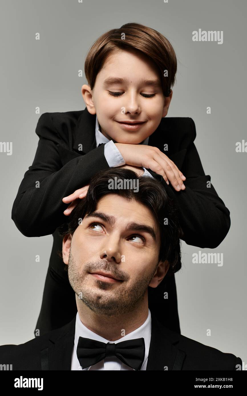 A young boy playfully places his hands on his fathers head, while the ...