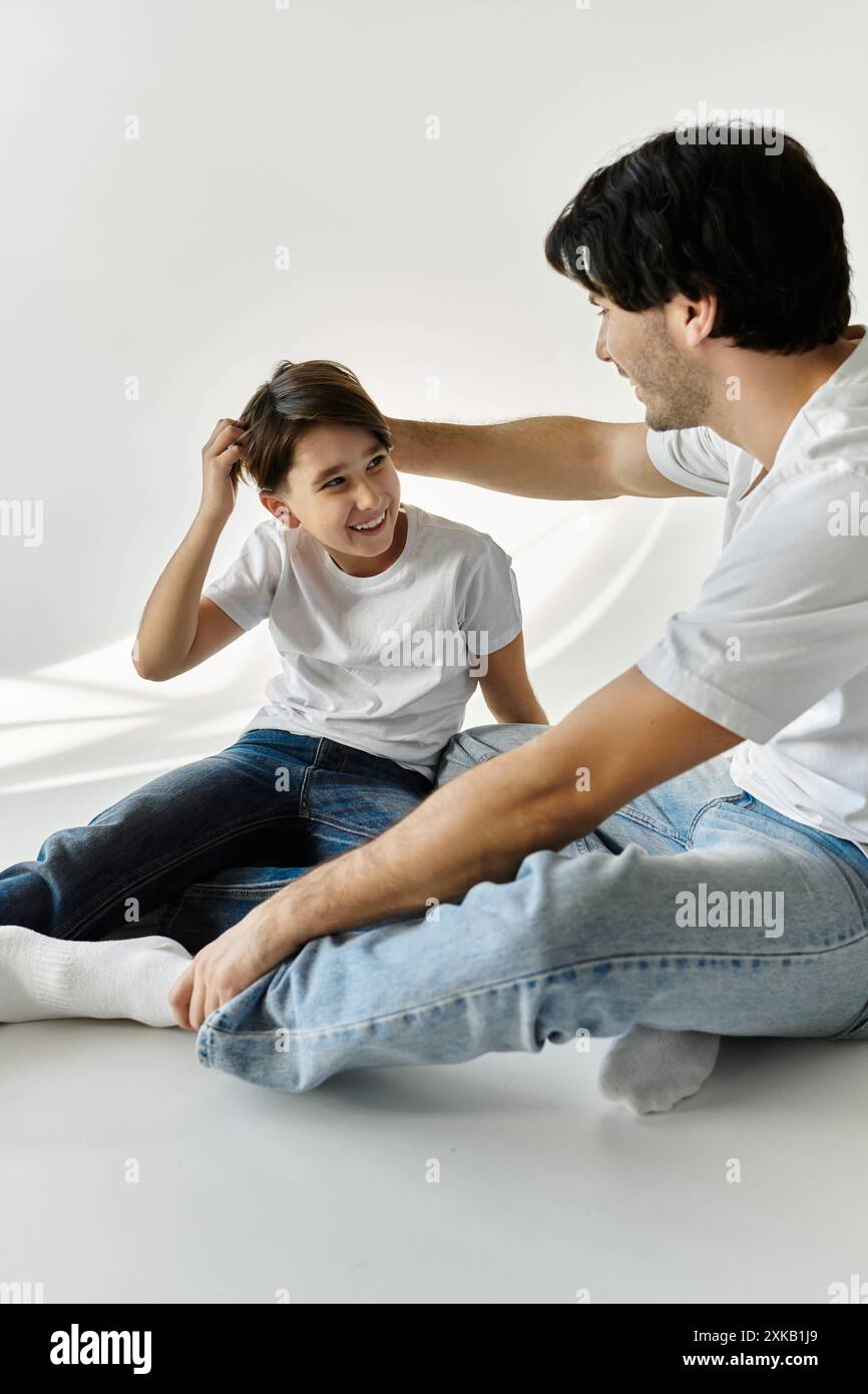 A father and son share a joyful moment, seated on the floor, the father ...