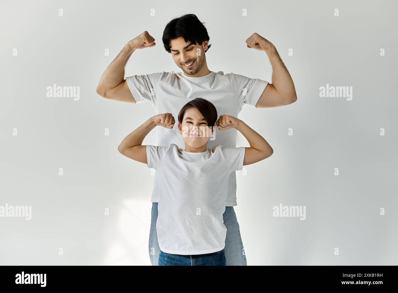 A father and son playfully flex their muscles, capturing a tender ...