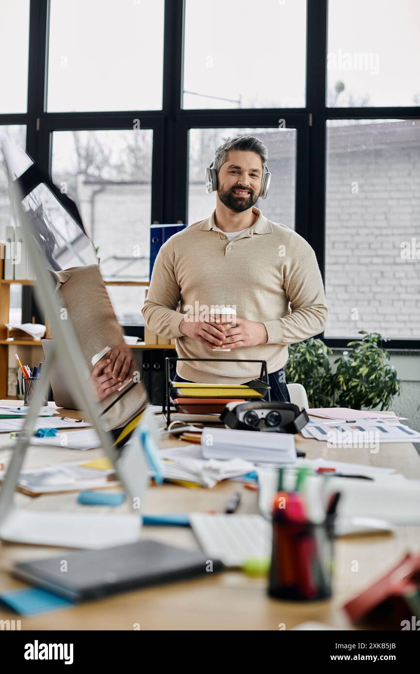 A handsome bearded businessman with headphones smiles while working in ...
