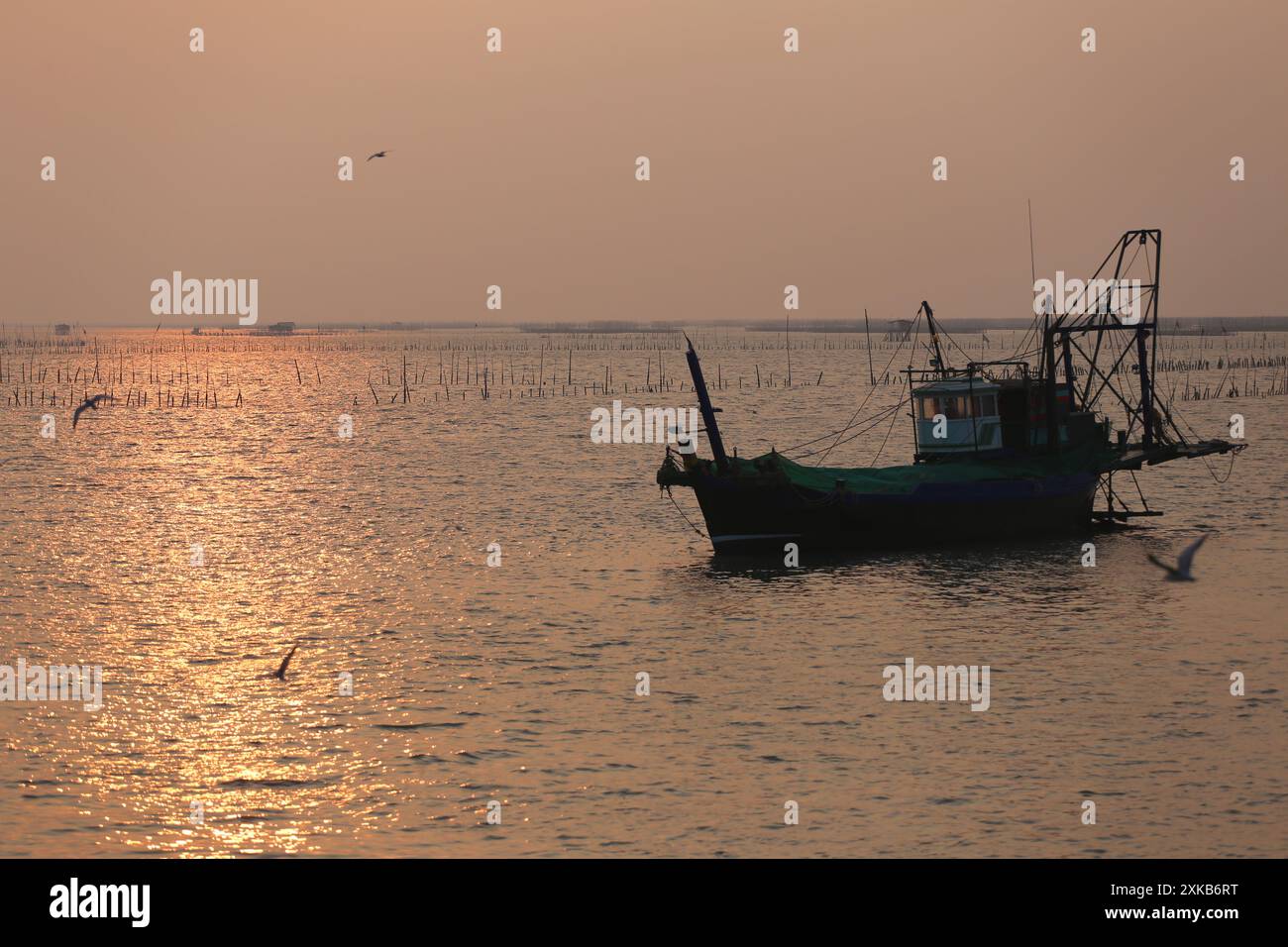 A local fishing boat is moored at sea and the background sunset in the ...