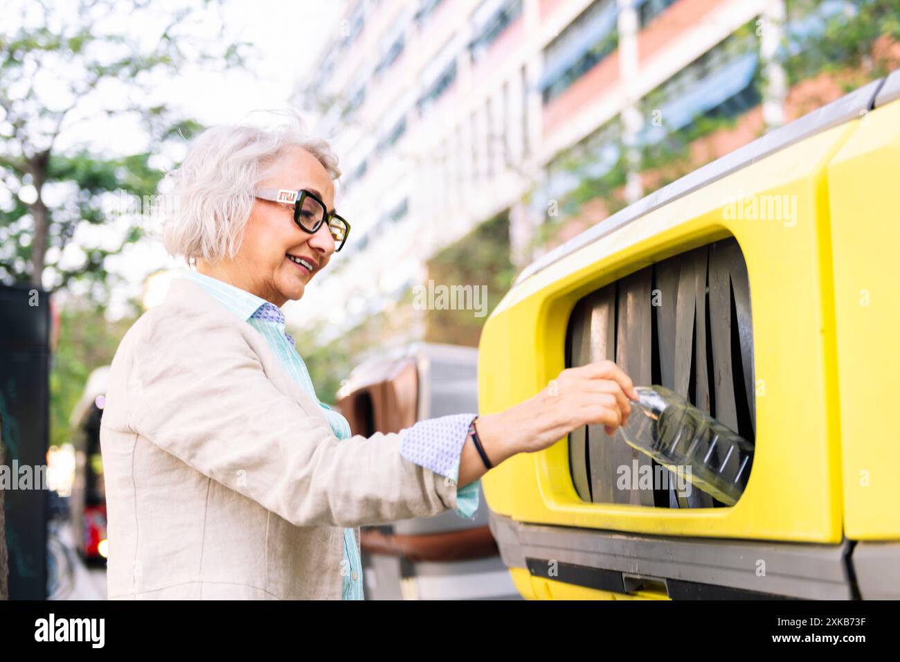 mature woman throwing plastic into recycling bin Stock Photo - Alamy