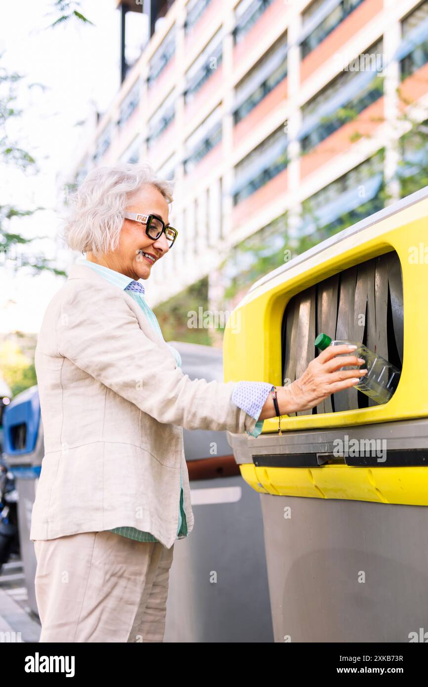 mature woman throwing plastic into recycling bin Stock Photo - Alamy