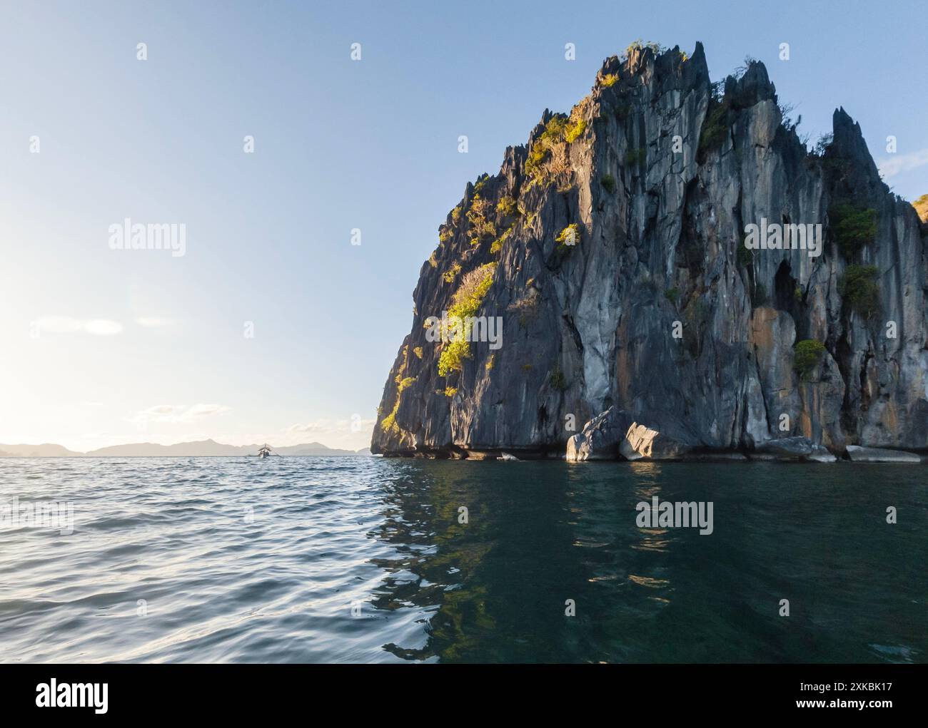 A large limestone cliff rises dramatically from the turquoise waters of ...