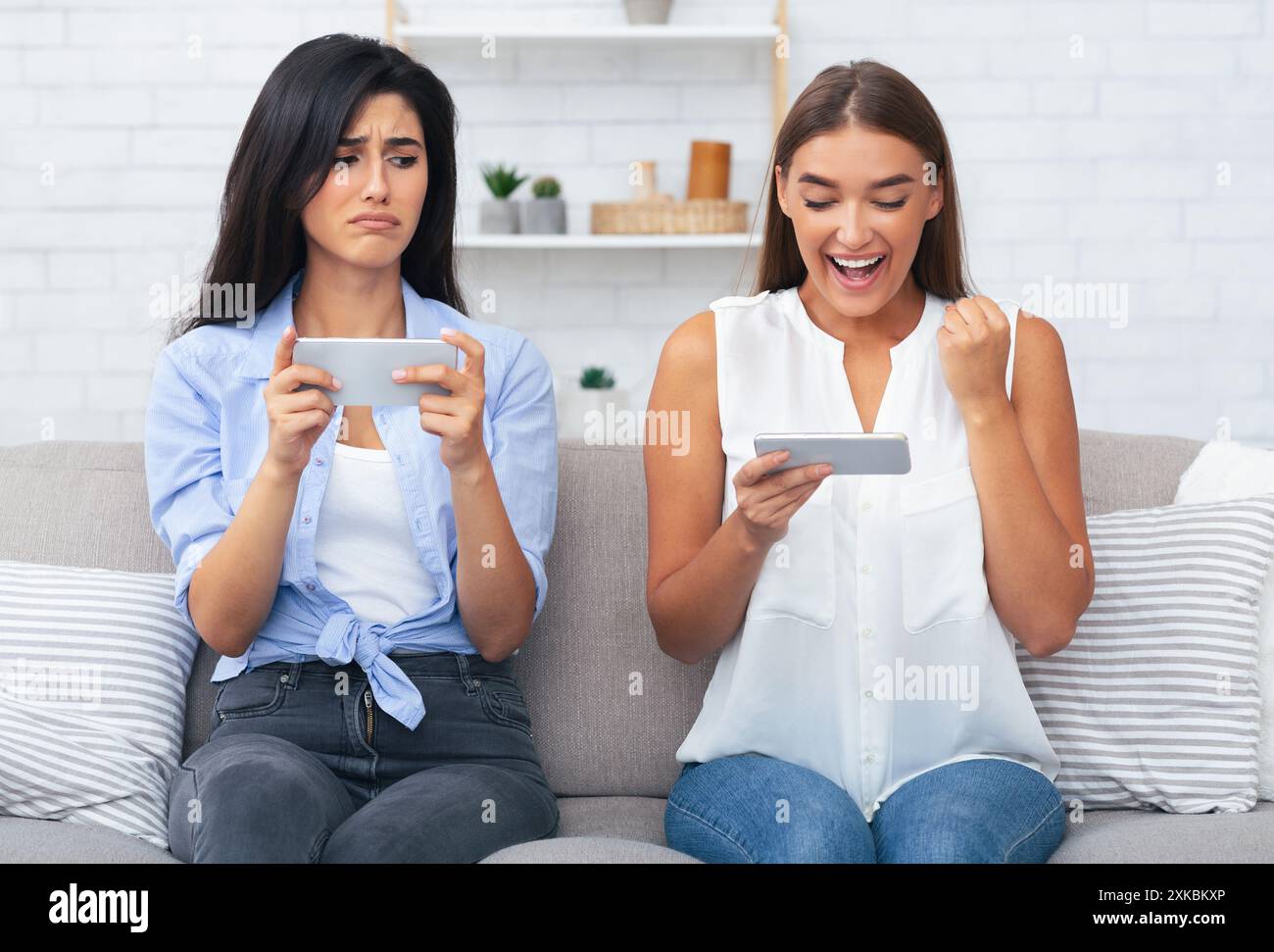 Girl being envious her friend's victory in mobile game indoor Stock ...