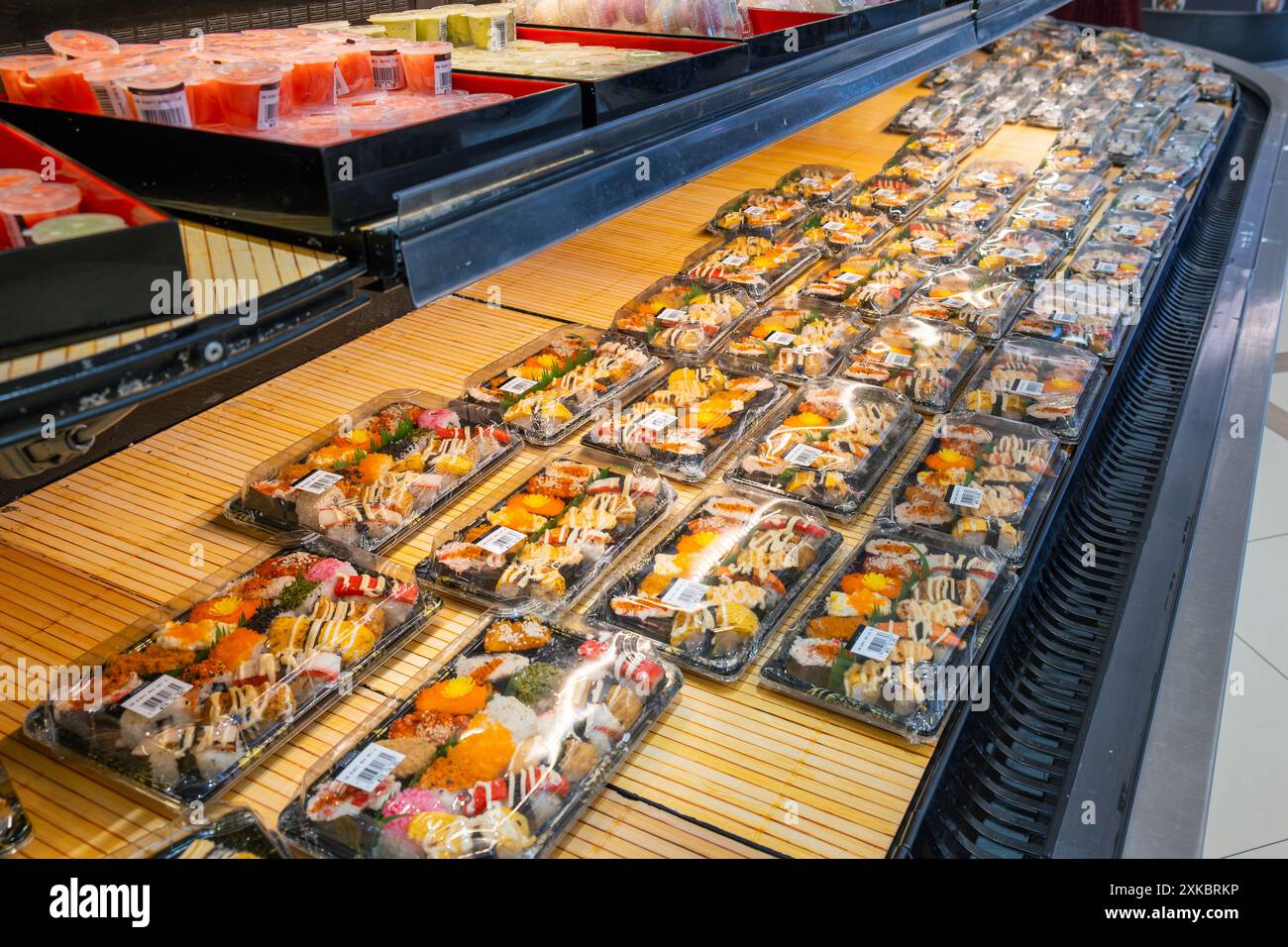 Assortment of packaged sushi trays displayed in refrigerated section at ...