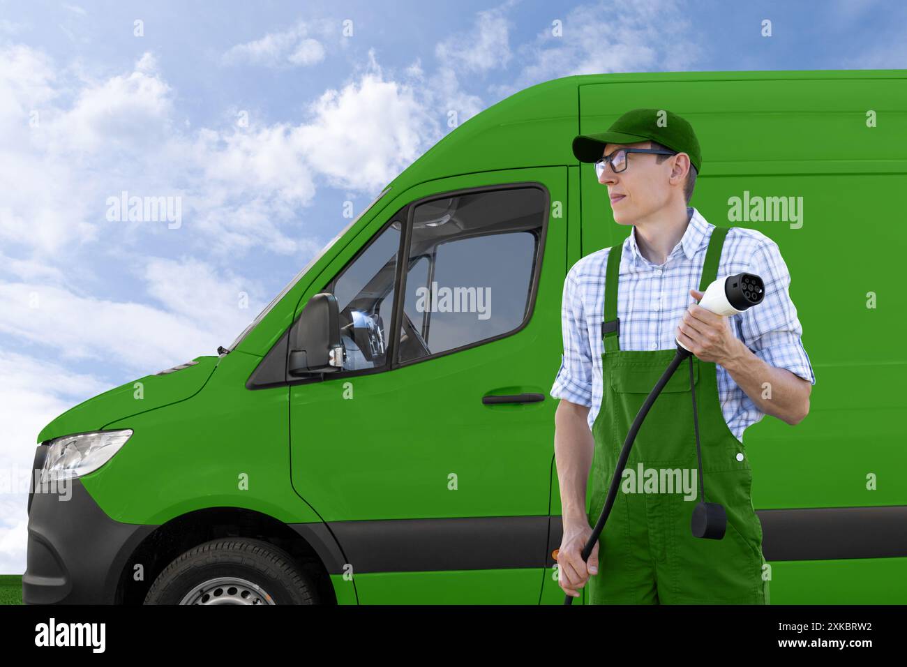 Man in uniform holds electric vehicle charging plug. Electric vans in ...