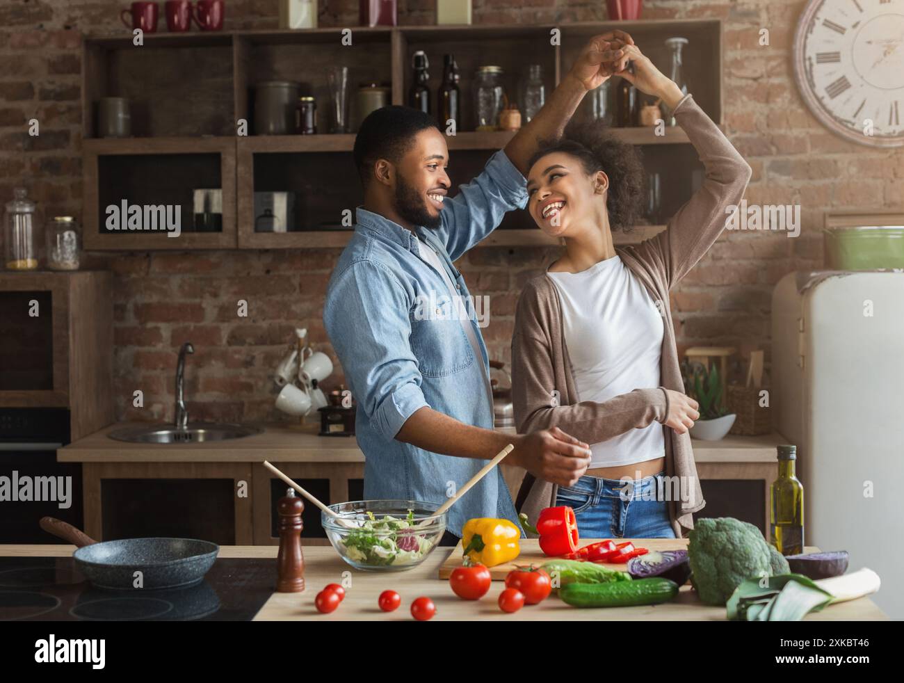 Happy romantic couple dancing in kitchen while cooking Stock Photo - Alamy