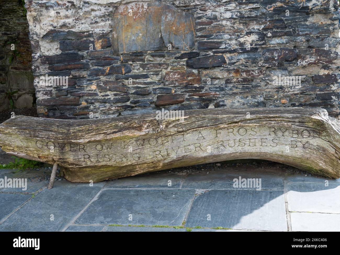 Old rough hewn tree trunk bench seat with carved inscription in old ...