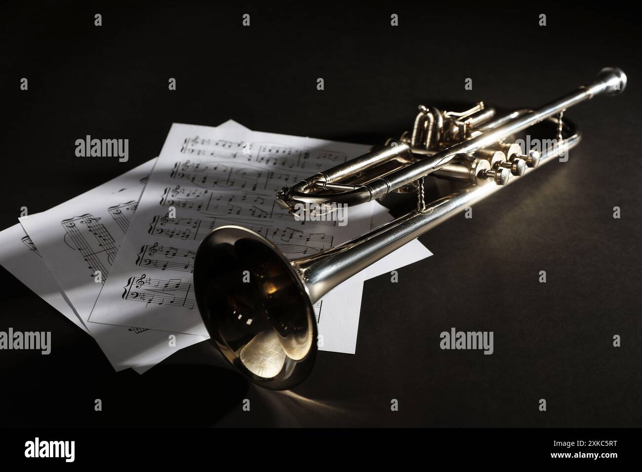 Shiny trumpet and music sheets on dark background. Wind musical ...