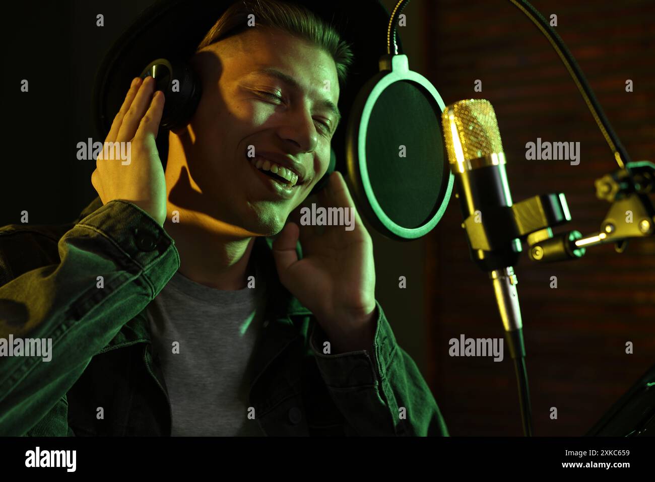 Vocalist with headphones singing into microphone in professional record ...