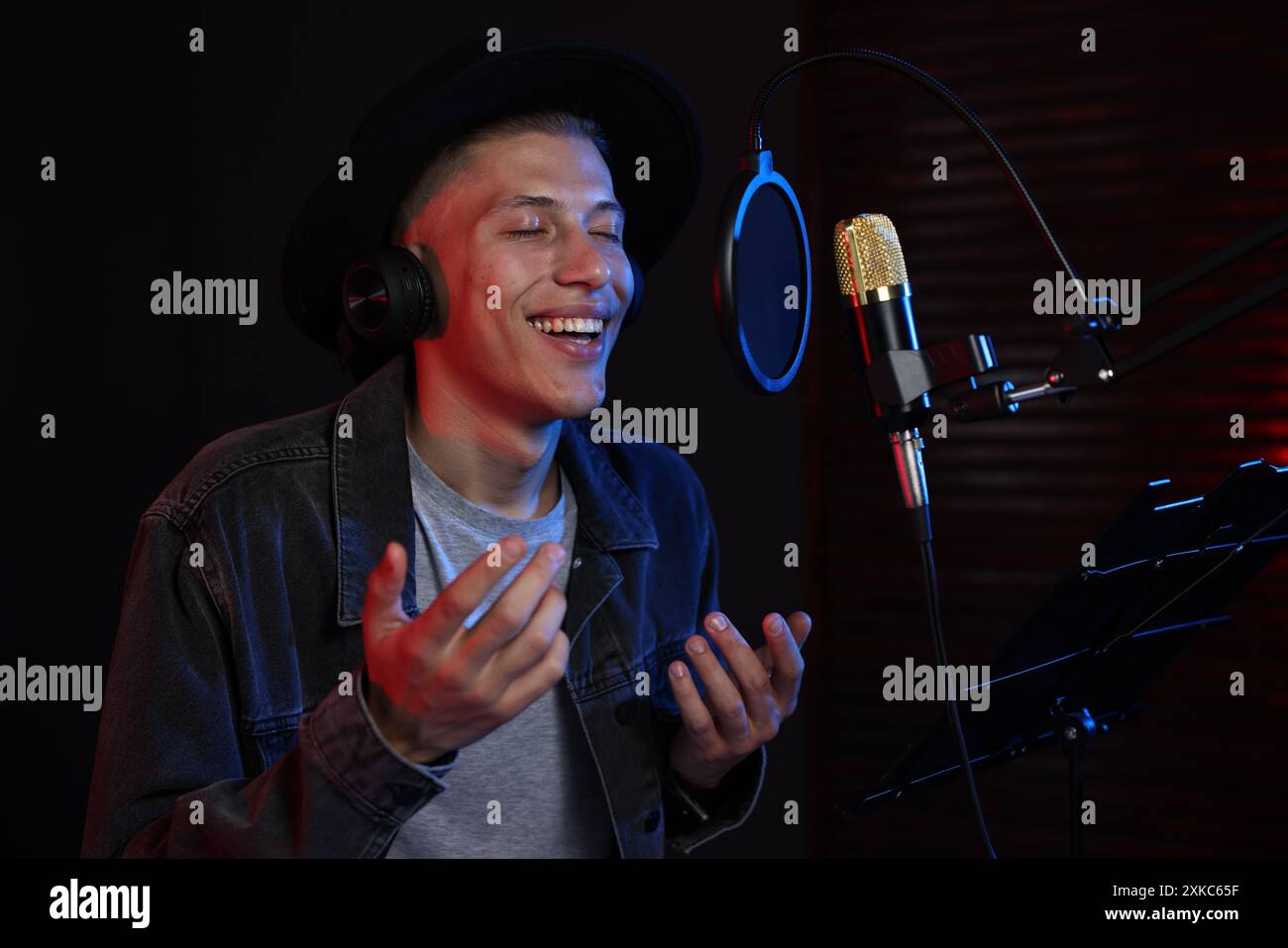 Vocalist with headphones singing into microphone in professional record ...