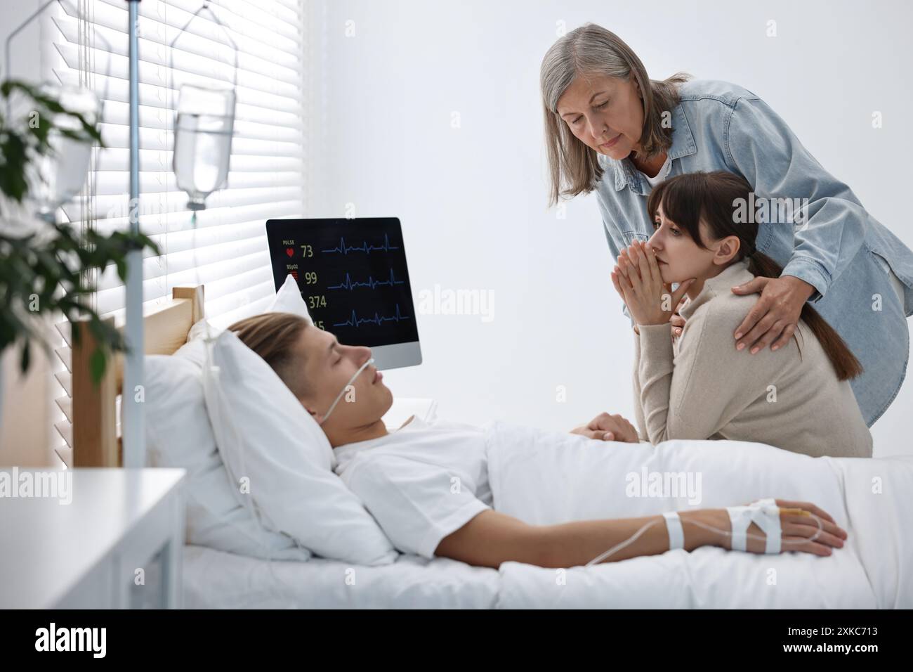 Coma patient. Sad women near unconscious young man in hospital Stock ...