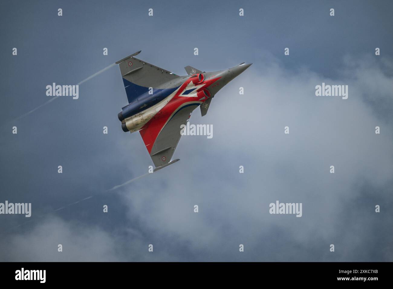 An aerobatic jet aircraft is executing a stunt maneuver with dramatic ...