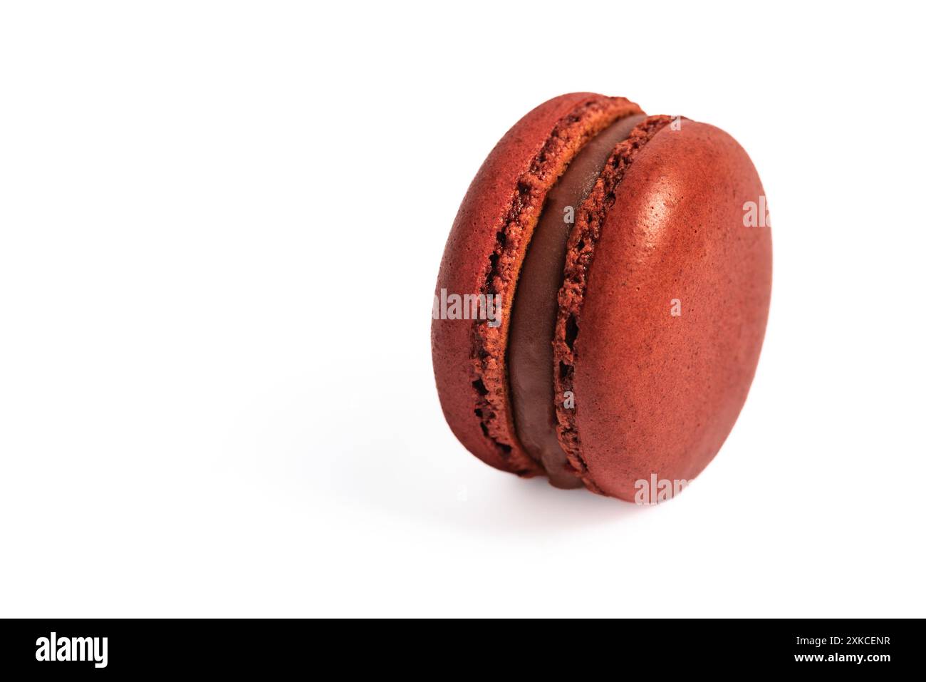 A single, red macaron with a strawberry filling is shown in a close-up ...