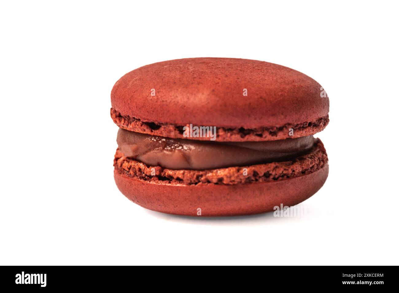 A single, red macaron with a strawberry filling is shown in a close-up ...