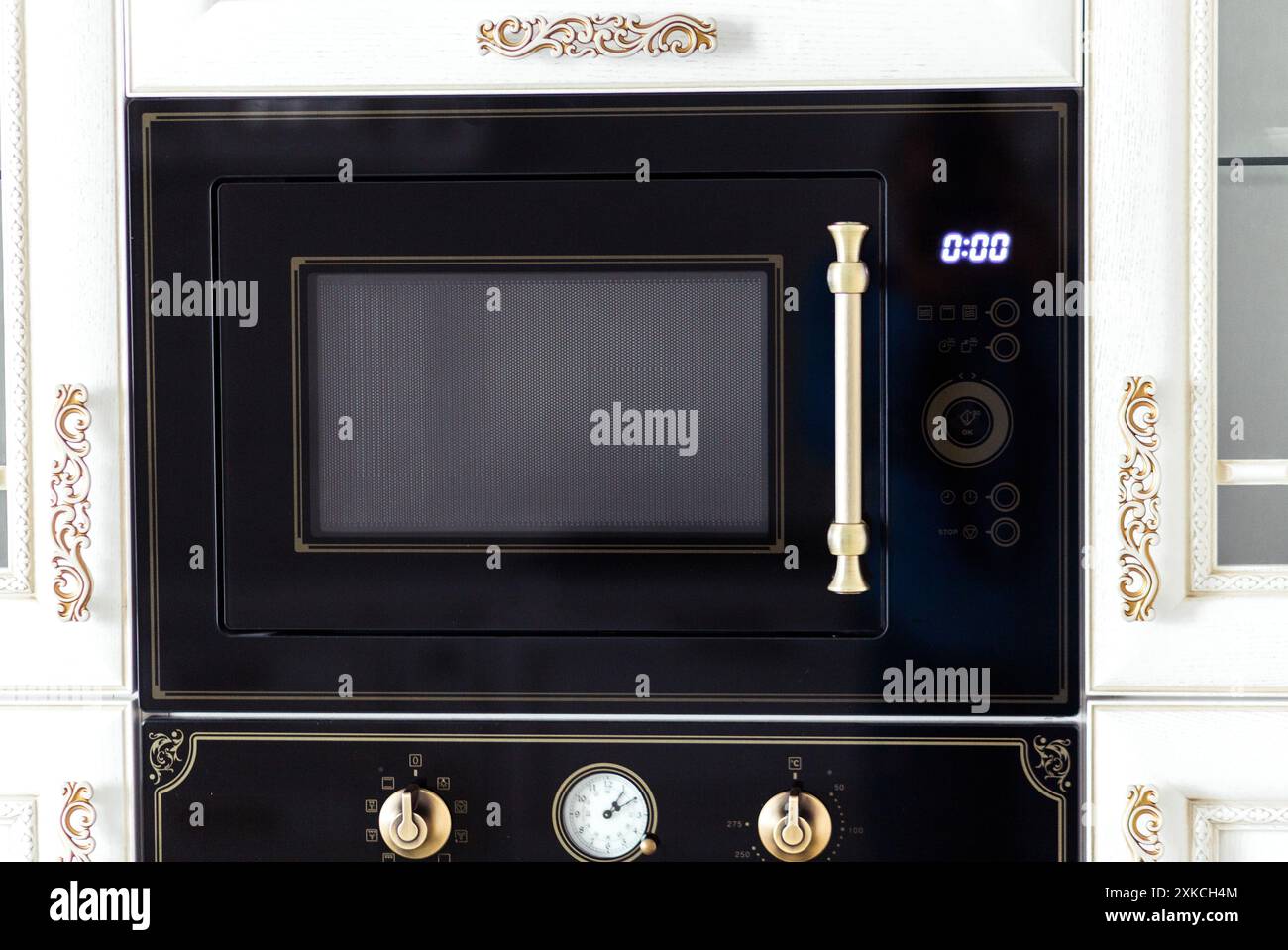 Close-up image of a modern black microwave oven with a brass handle ...