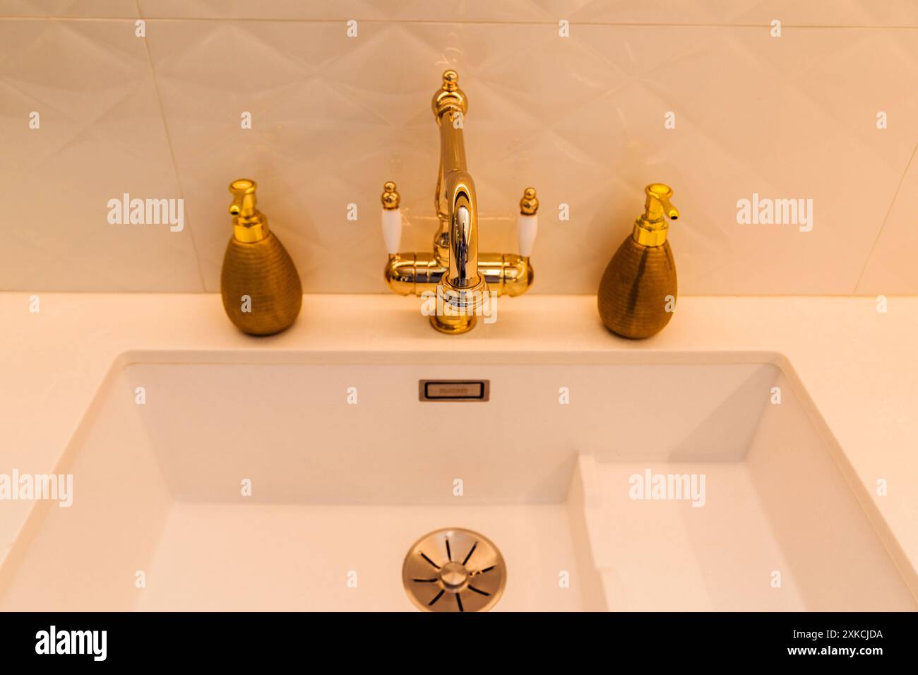 Top view of a luxurious gold faucet with matching soap dispensers on a ...