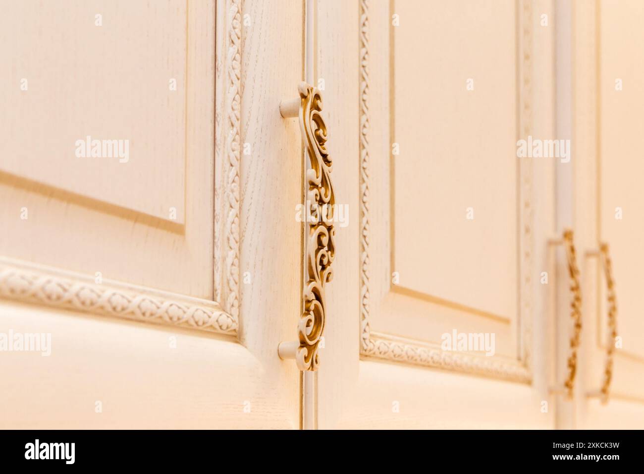 A close-up view of a white kitchen cabinet door, featuring an ornate ...