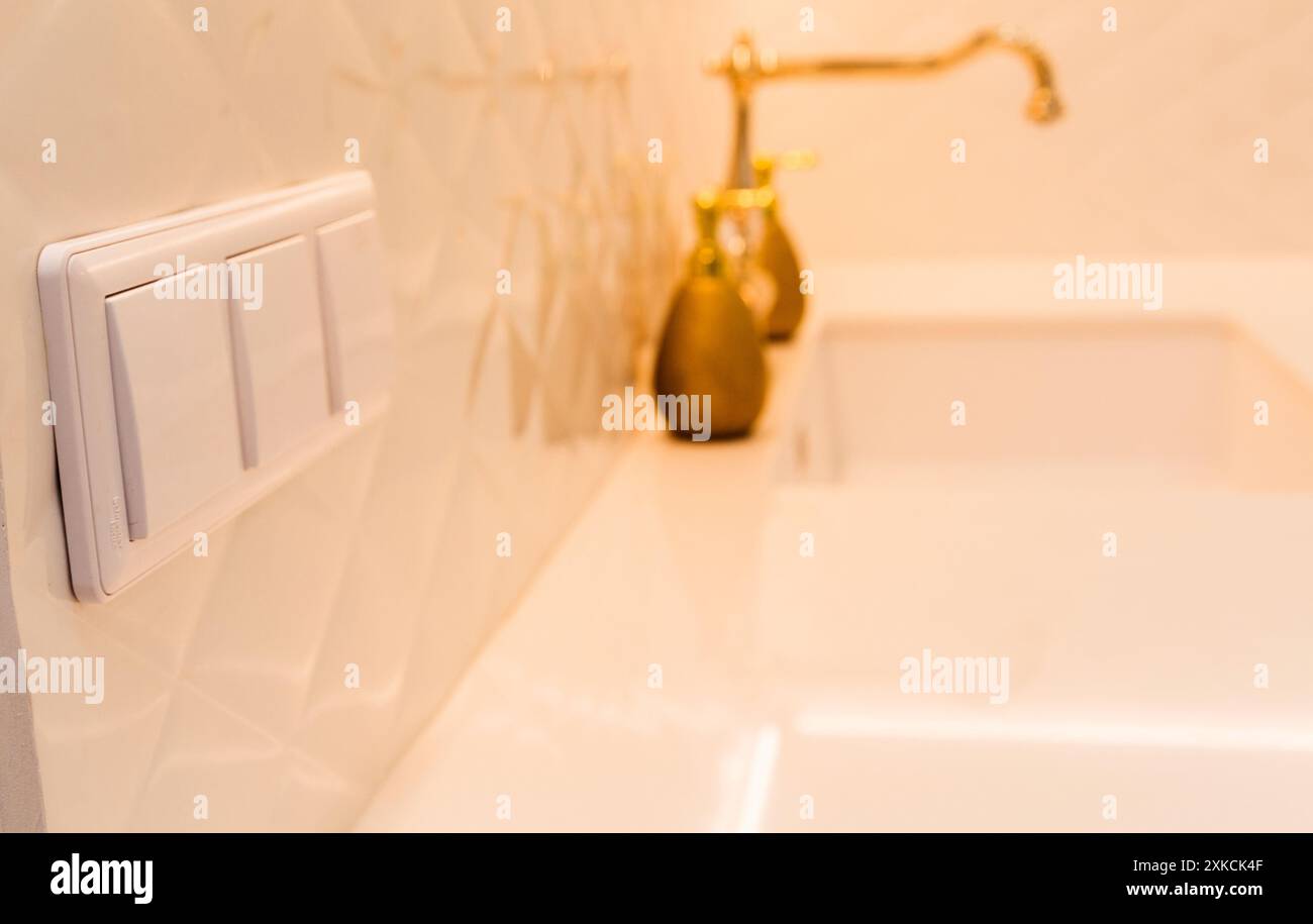 A close-up of a modern white kitchen switch on a tiled backsplash ...