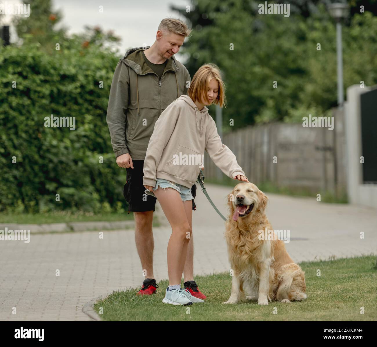 Dad And Daughter Play With Their Golden Retriever Dog During A Walk Stock Photo - Alamy