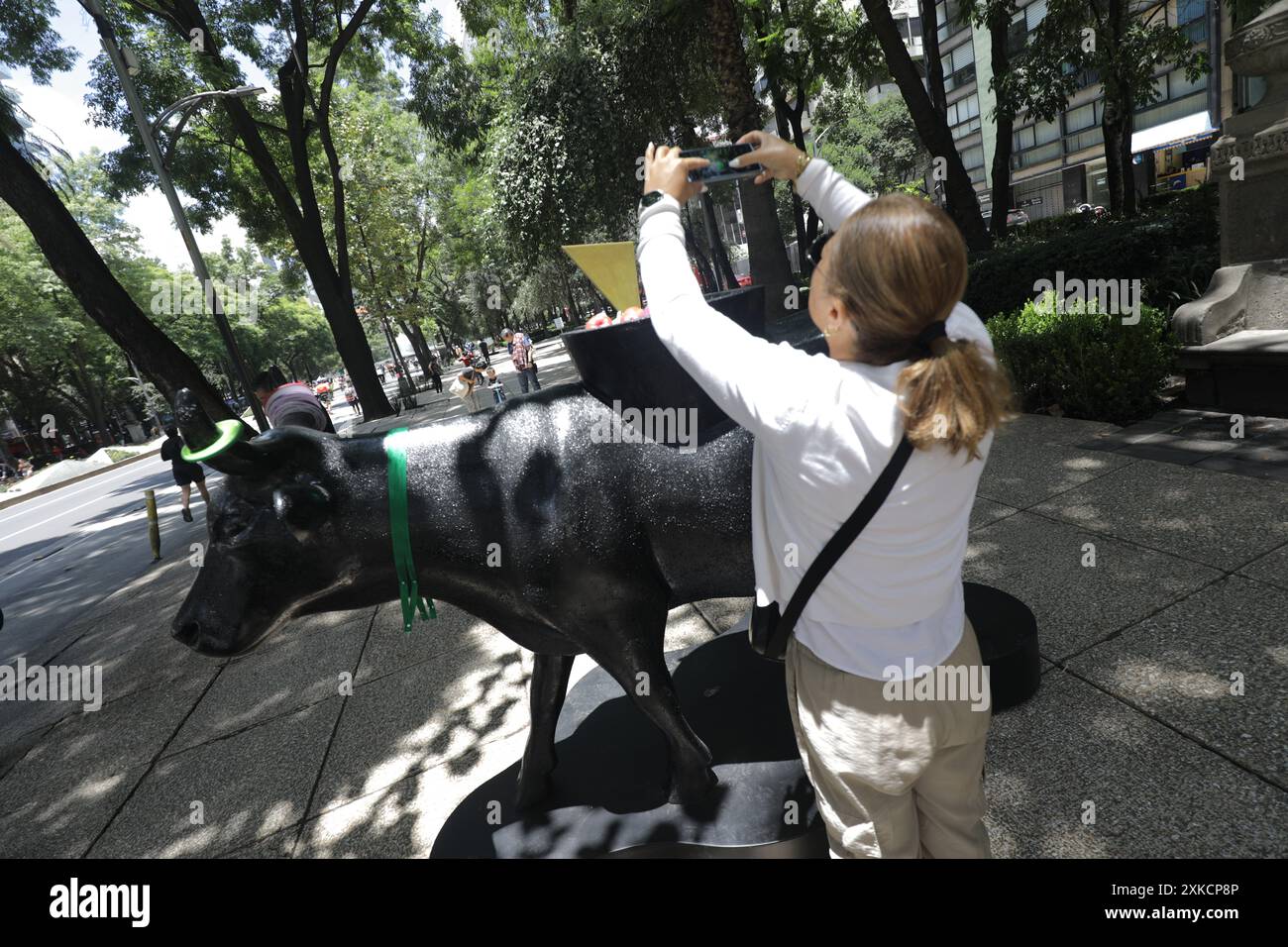 A woman takes a photo of a fiberglass cow painting by an artist during ...