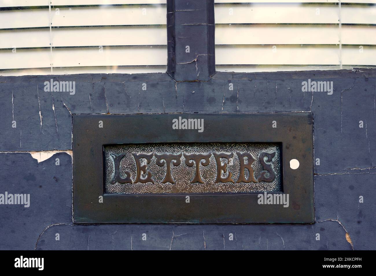 Closeup of an ornate letters mail slot in the front door of an old ...