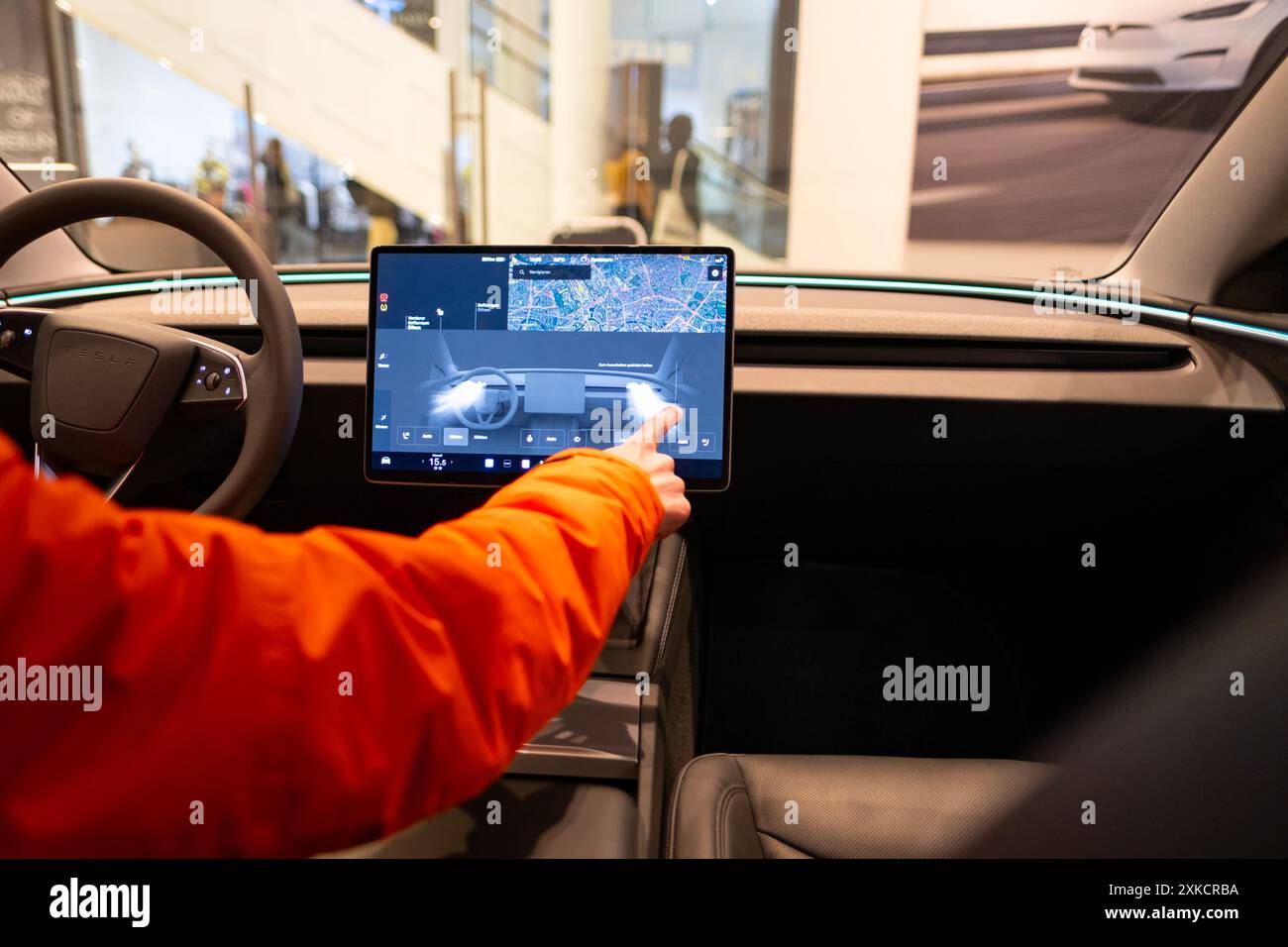 Close-up male hands uses display, gripping steering wheel Tesla model Y ...