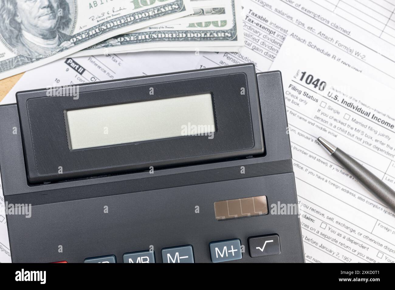 Calculator with blank screen, tex forms and dollar banknotes on table ...