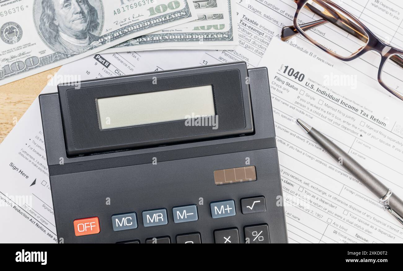 Calculator with blank screen, tex forms and dollar banknotes on table ...