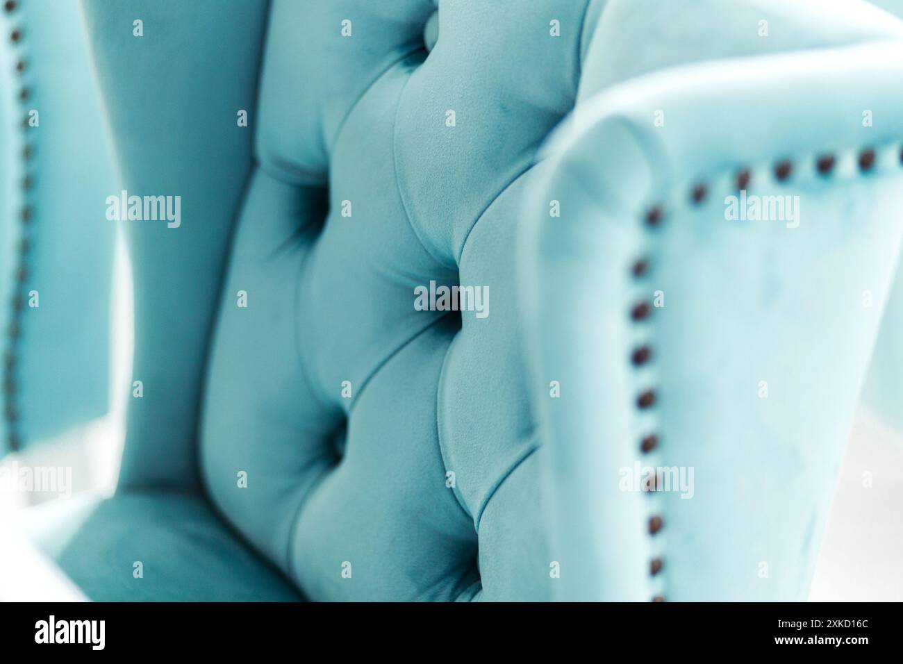 Close-up shot of a luxurious blue upholstered chair with tufted buttons ...