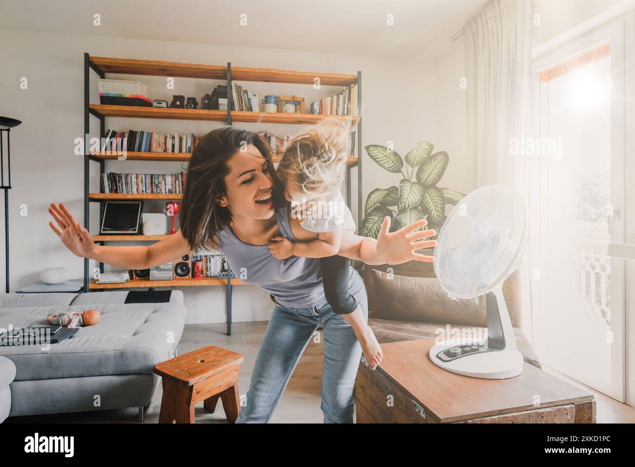 Mother and daughter beat the summer heat at home, playing with an ...