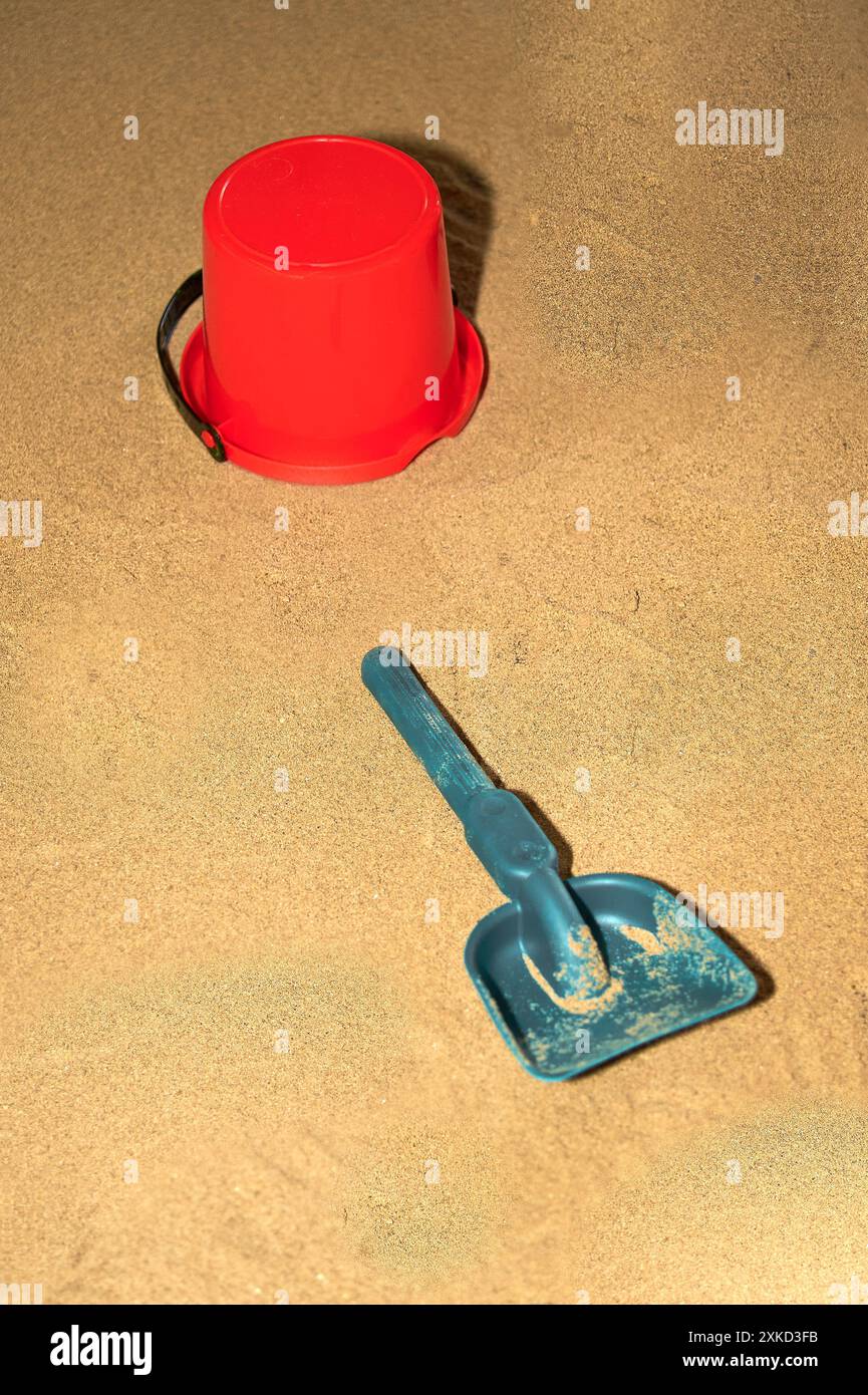 Summery scene with a red bucket and a mound of sand, evoking memories ...