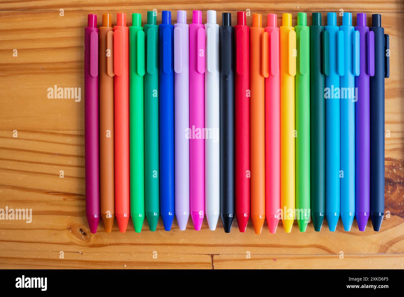 Multi-colored pens are stacked on a black desk in the designer's office ...