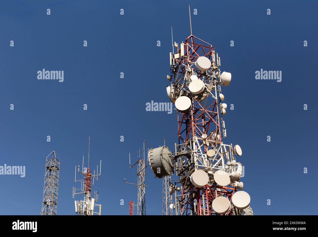 A tall communications tower with many antennas on top. The sky is blue and clear. The tower is ...