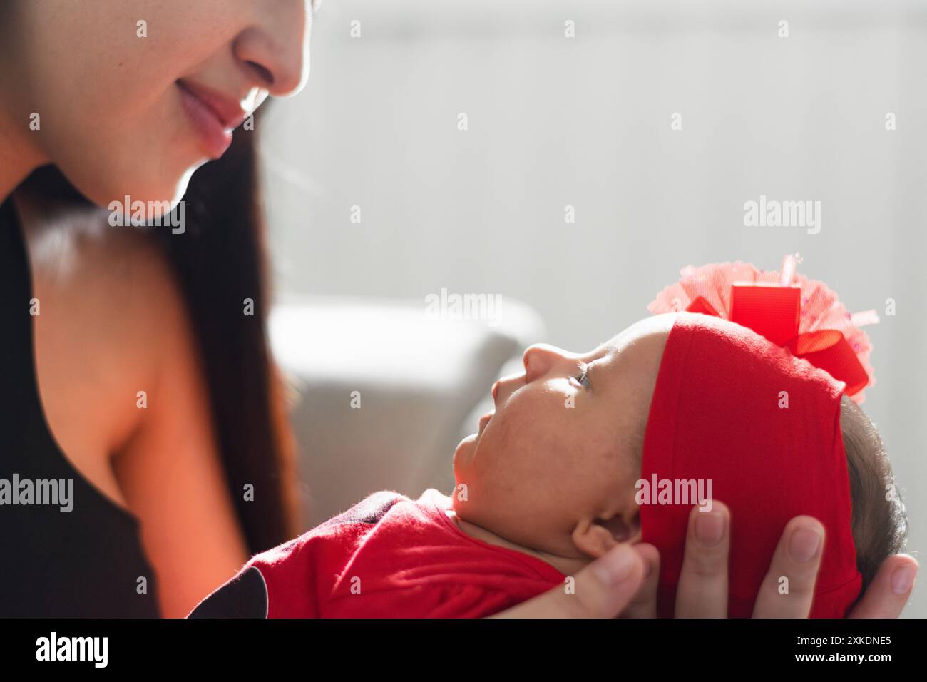 close-up of newborn baby girl looking at her mother while being carried ...