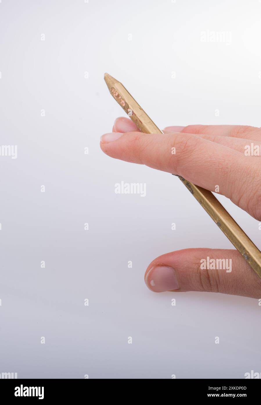 Hand holding a gold color pencil on a white background Stock Photo - Alamy
