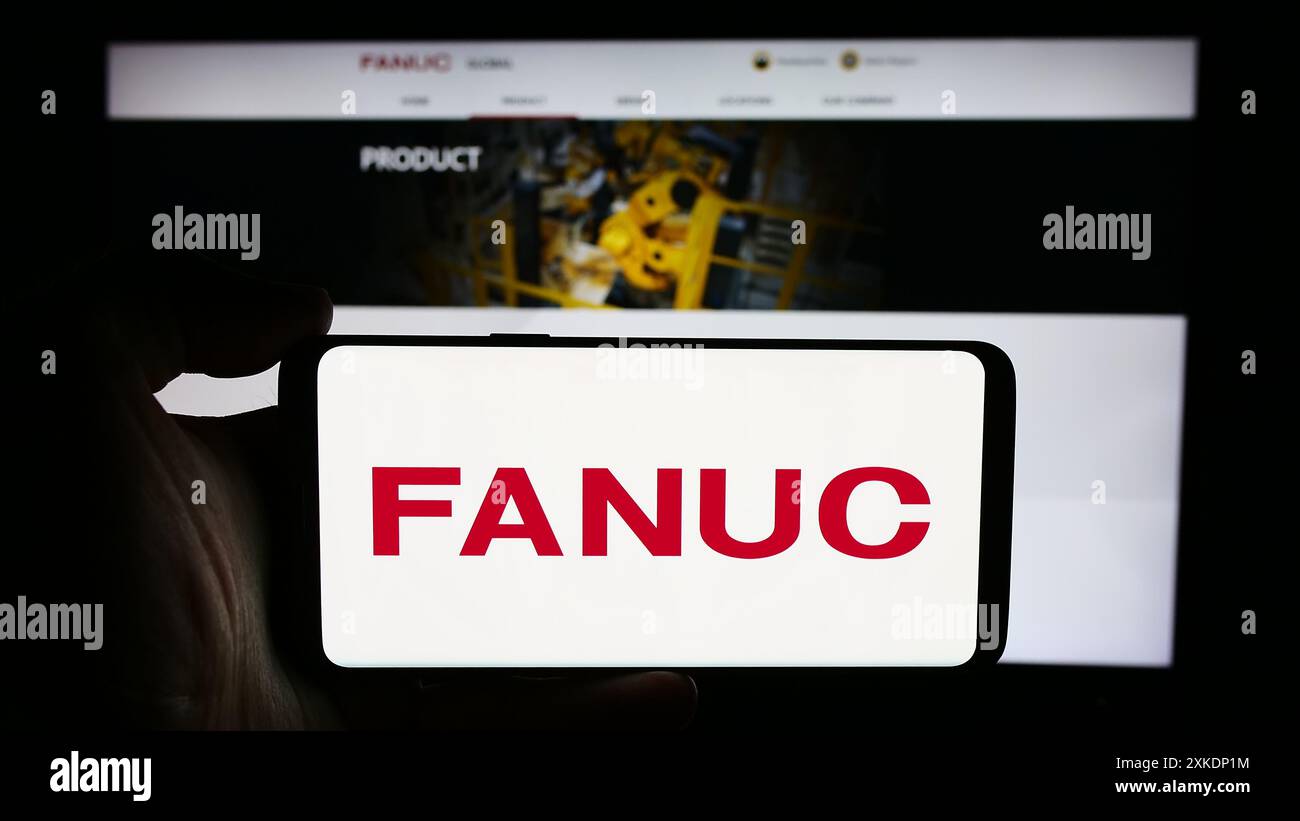Person holding cellphone with logo of Japanese robotics company FANUC ...