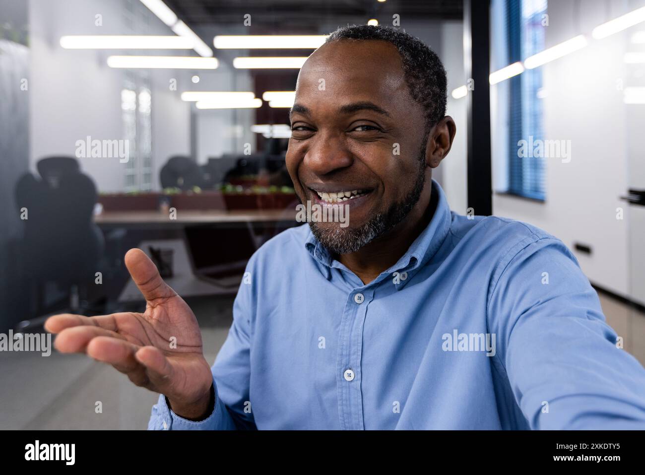 Confident businessman smiling and gesturing during video call in modern ...