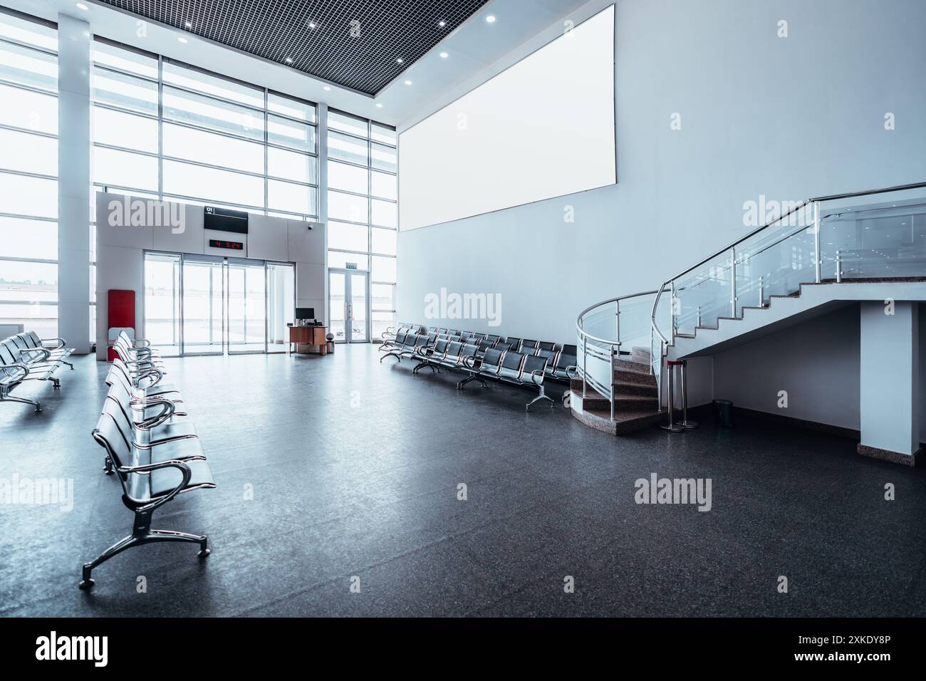 Spacious airport waiting area with rows of empty chairs, large windows ...