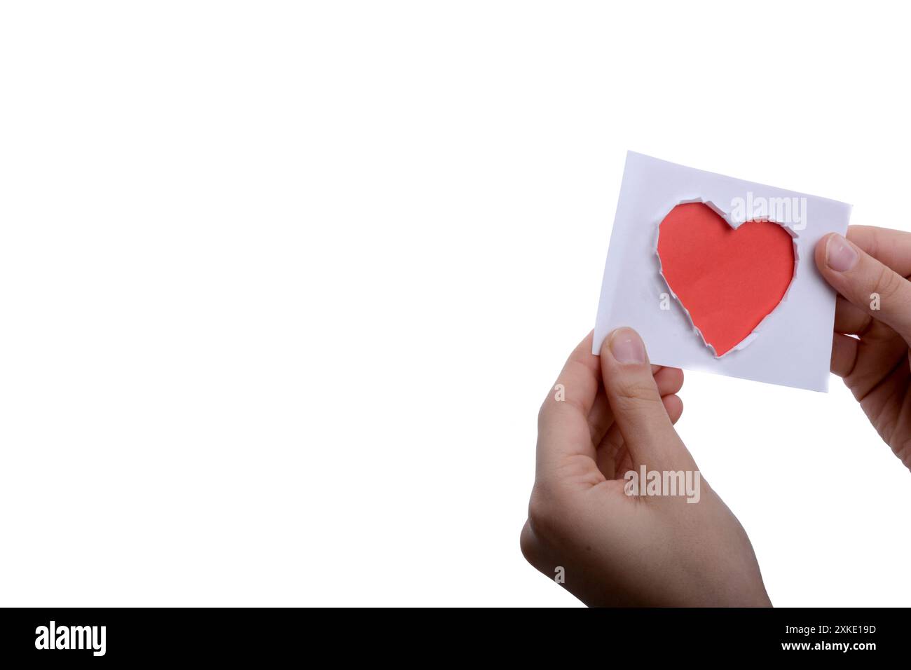 Hand holding a red heart shape paper cut out of paper on a white ...