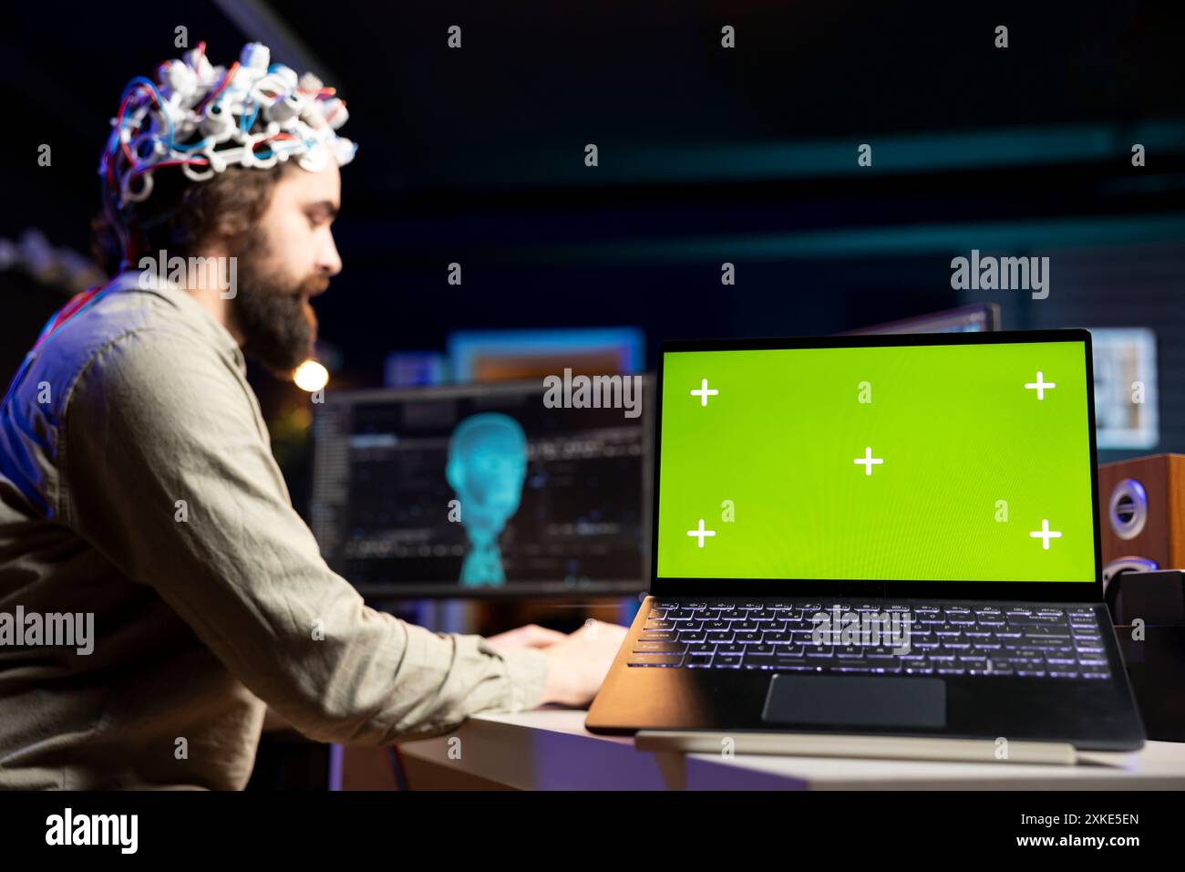 Focus on green screen laptop used by programmer using EEG headset to upload mind into PC. Close ...